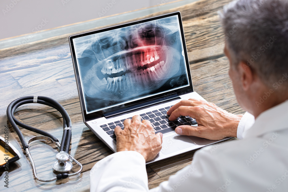 Dentist Typing On Laptop With Dental X-ray On Screen Stock Photo ...