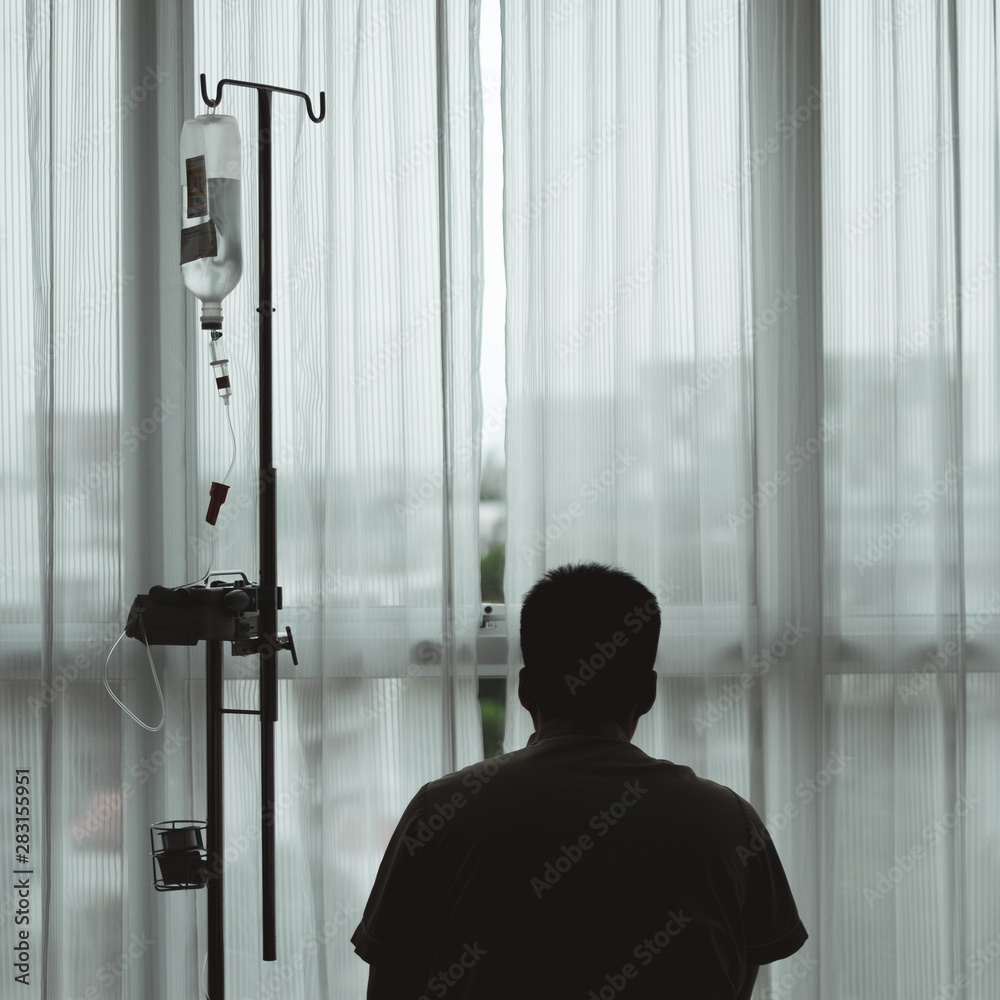 Silhouette male worried patient sitting and look out the hospital ...
