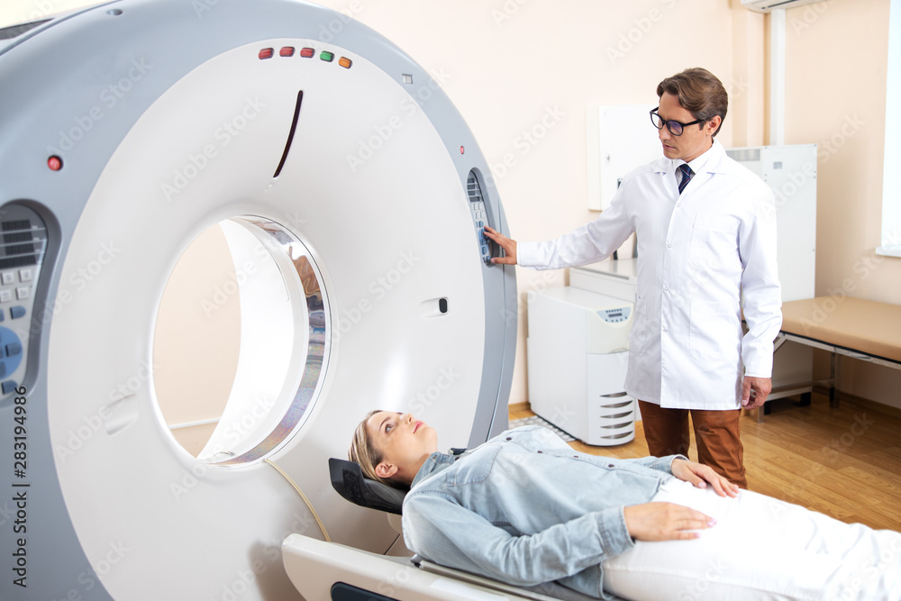 Young woman lying on CT scanner bed during tomography test in hospital ...