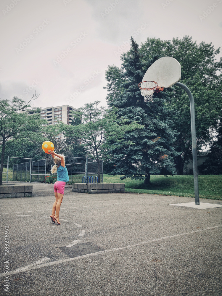 Preschool Caucasian child girl playing basketball with orange yellow ...