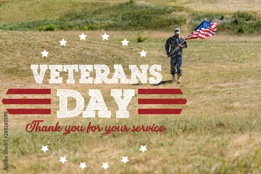 Handsome soldier in uniform walking and holding American flag in ...