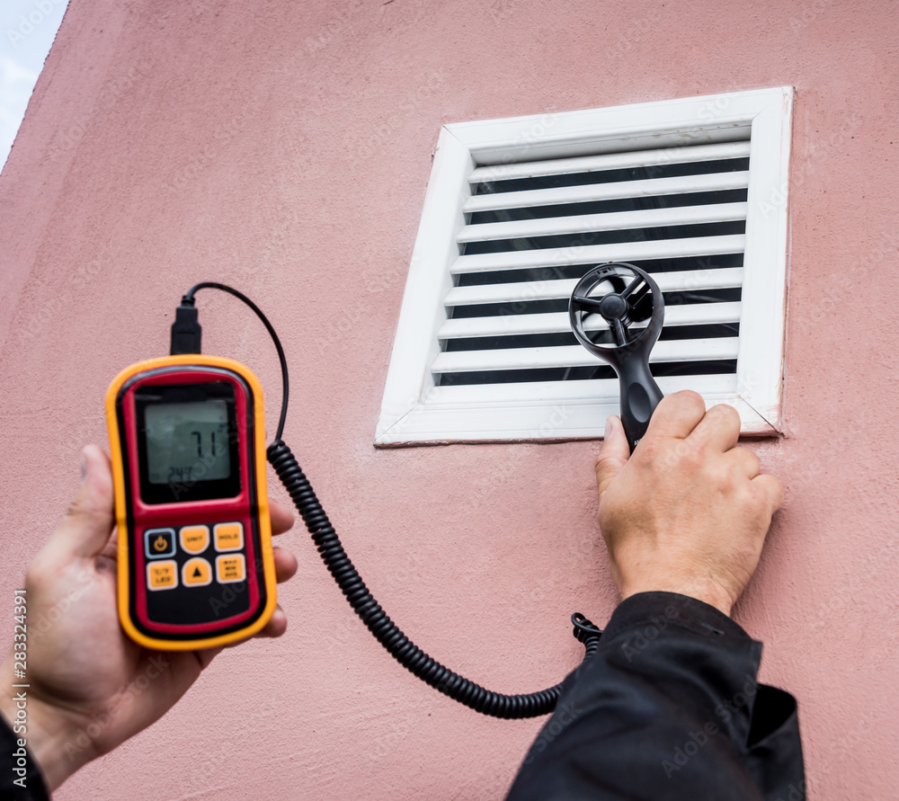 Technician use hand-held anemometer measuring air flowing measurement ...