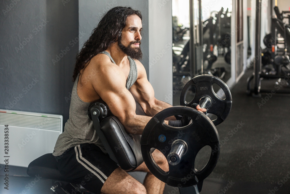 Side view portrait of young adult bodybuilder with long curly hair are ...