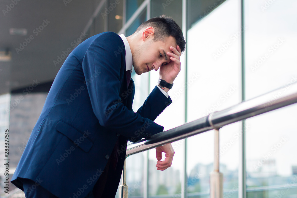 Tired upset businessman leans on the railing. Depressed young man in ...