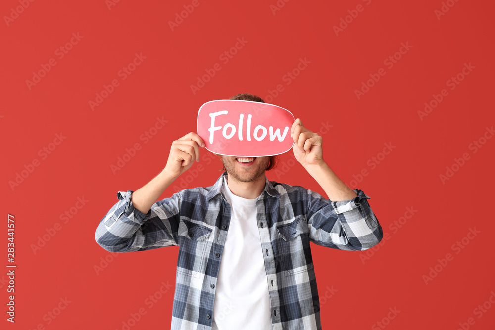 Male blogger holding paper with text FOLLOW on color background Stock ...