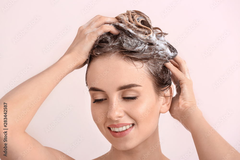 Beautiful young woman washing hair against light color background Stock ...
