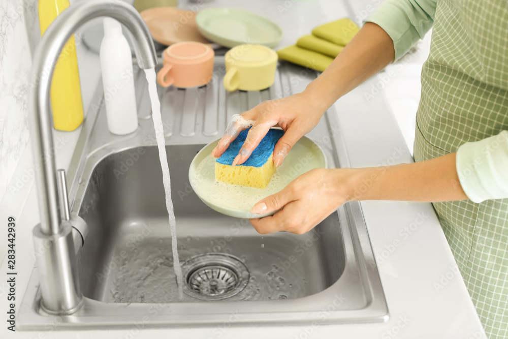 Woman washing dishes in kitchen sink Stock Photo | Adobe Stock