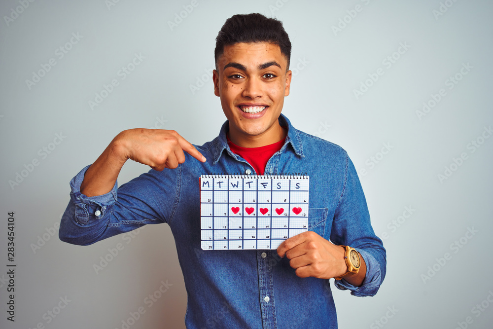 Young brazilian man holding calendar standing over isolated white ...