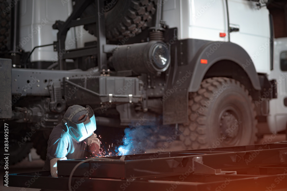 Welder in a car workshop welds a truck frame Stock Photo | Adobe Stock