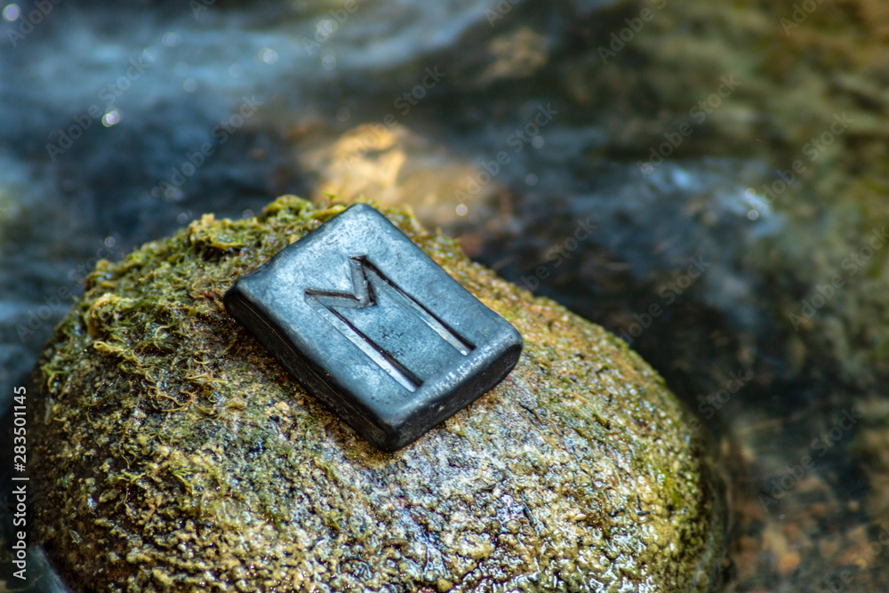 Norse rune Ewaz on the stone and the evening river background. Air ...