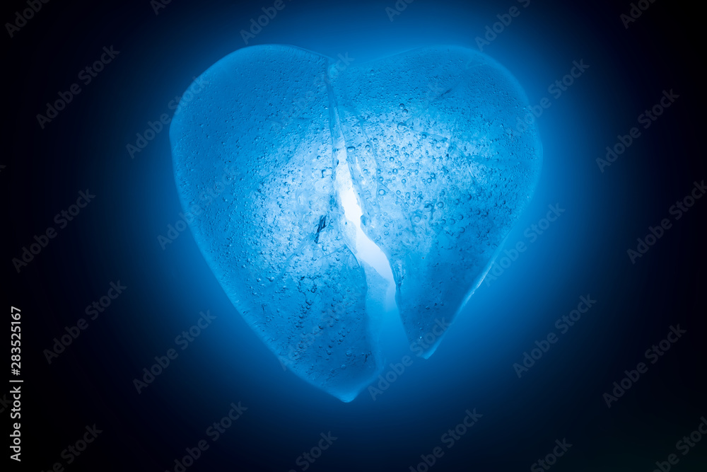 Ice frozen broken in half heart symbol of blue color close-up glowing ...