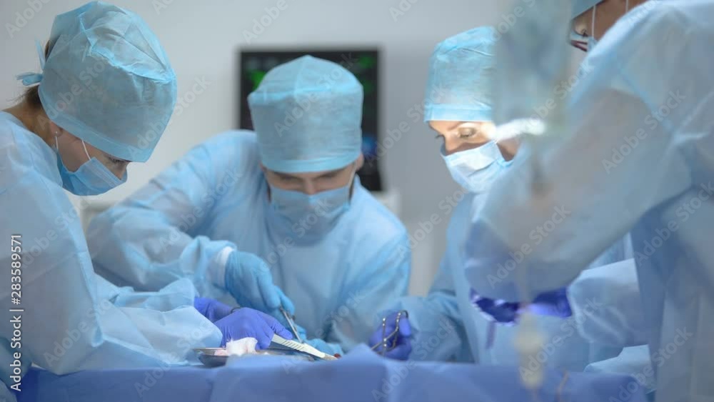 Medical drip bag on background of surgeon team working in operation ...