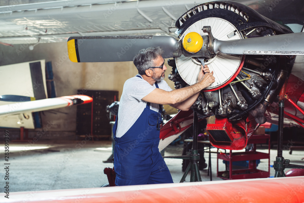 Aircraft mechanic repairs an aircraft engine in an airport hangar Stock ...