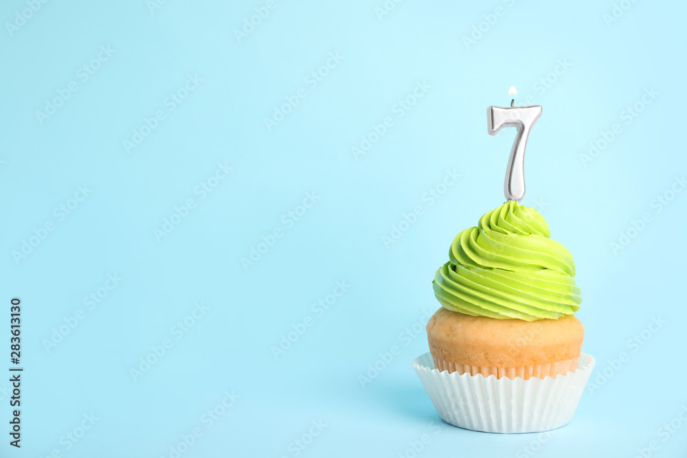 Birthday cupcake with number seven candle on blue background, space for ...