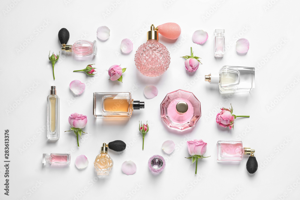 Poster Different perfume bottles and flowers on white background, top ...