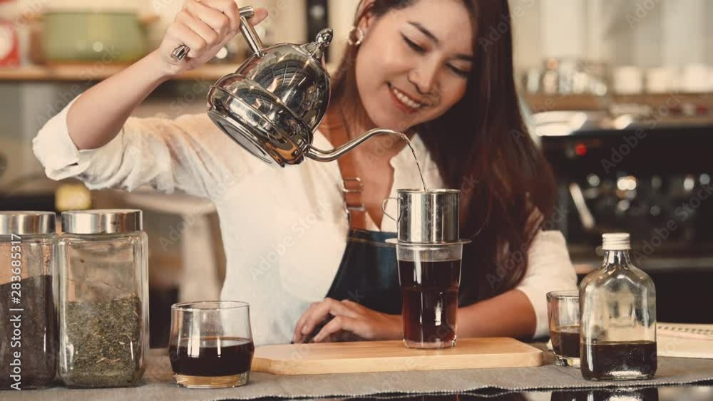 Asian professional female barista making cup of coffee at counter bar ...