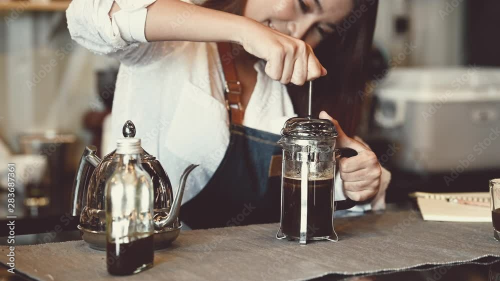 Asian professional female barista making cup of coffee at counter bar ...
