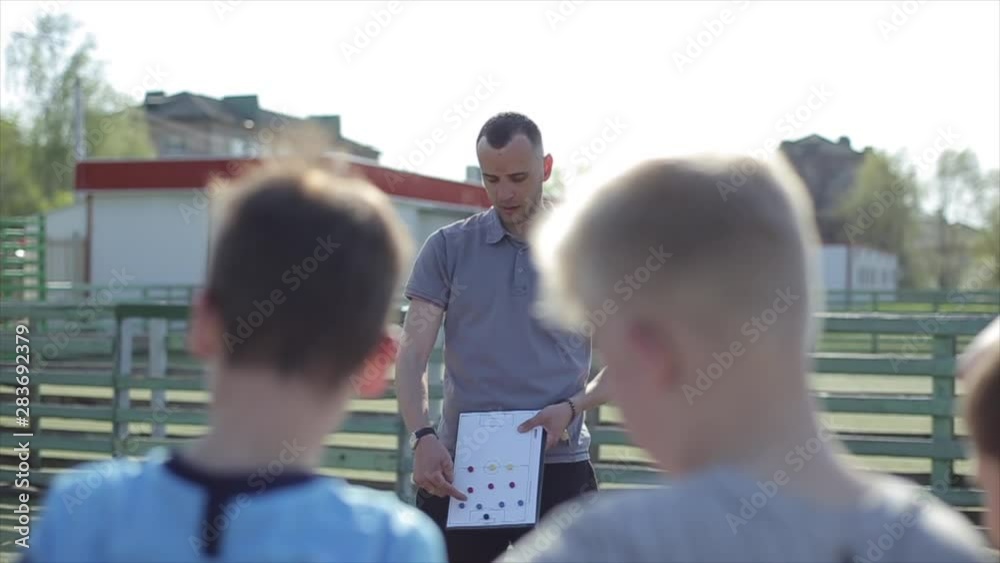 Young Football coach trainer coaching kids using tactic strategy ...