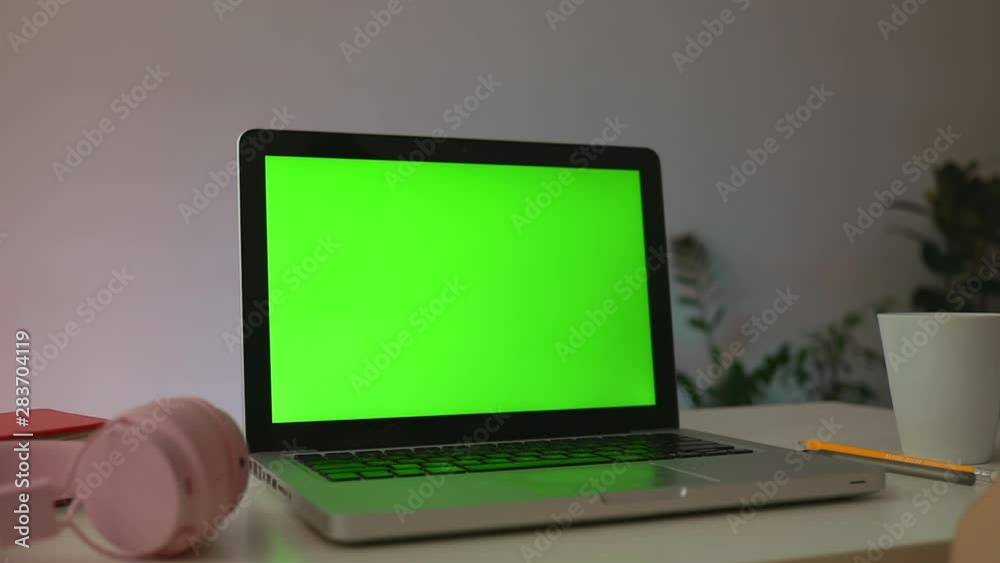 Laptop with green screen. Dark office. Dolly in. Perfect to put your ...