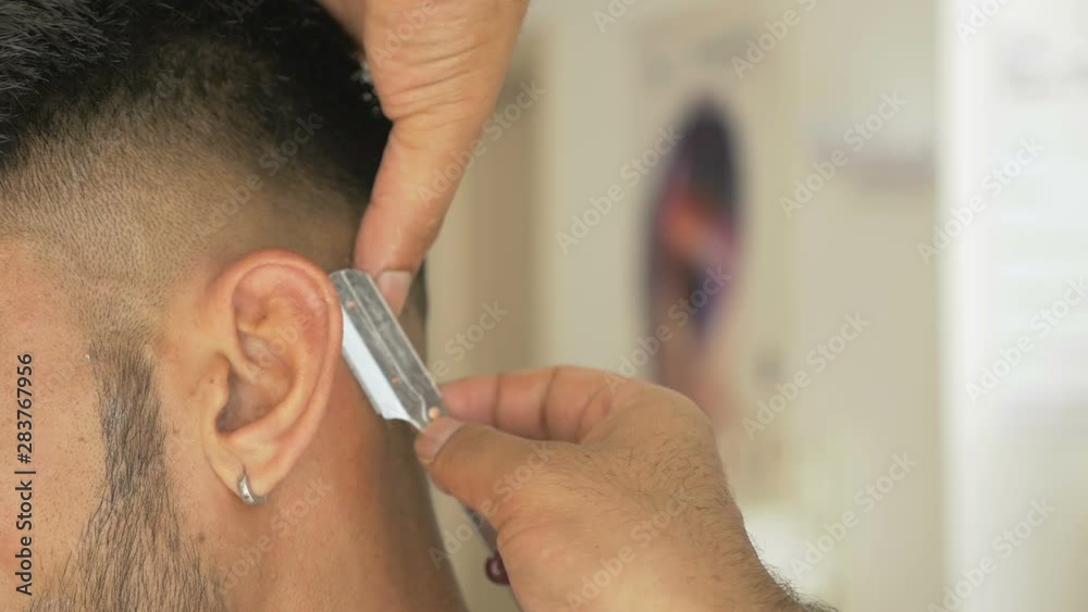 Stylish barber shaves his client neck in an old-fashion manner. Young ...