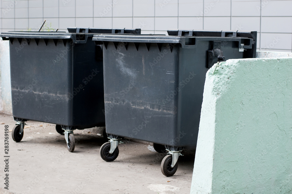 Dumpsters on the grey wall background. Garbage bins near housing Stock ...