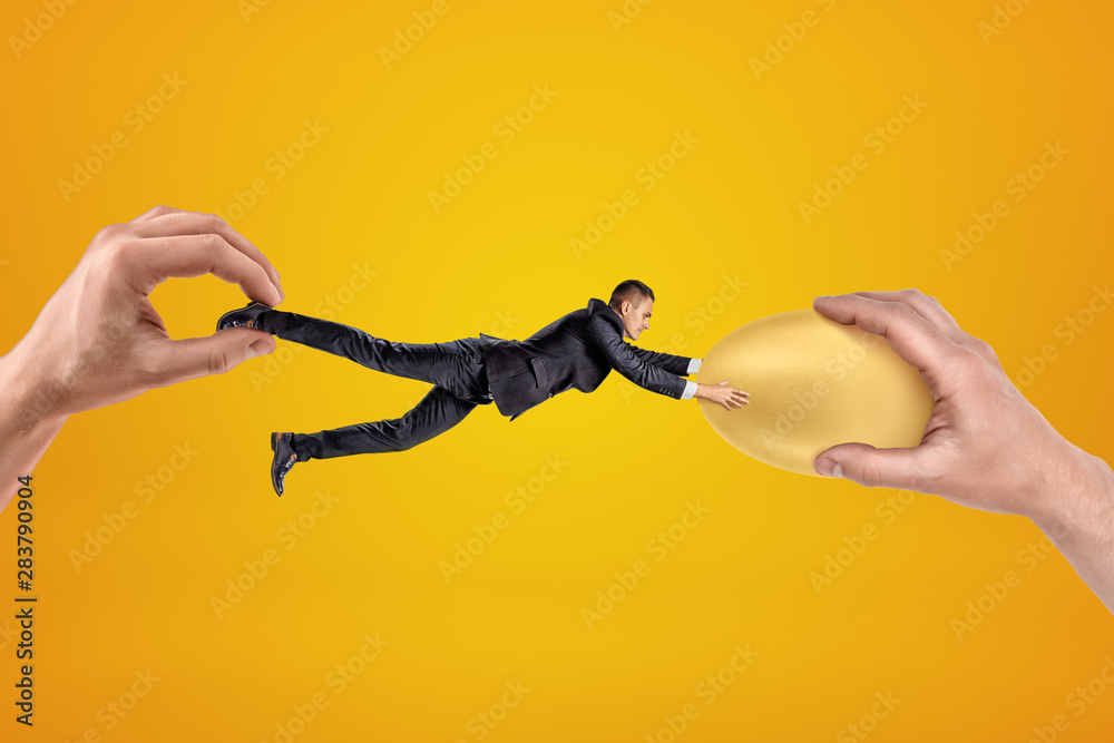 Small businessman being pulled in opposite directions by two big hands ...