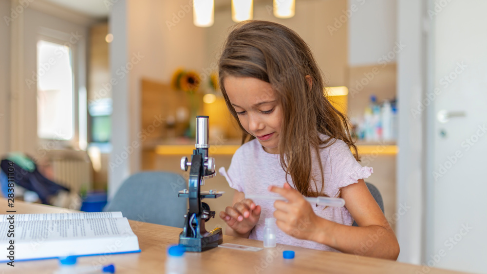 Preschool age girl looks into microscope. Child playing science in the ...