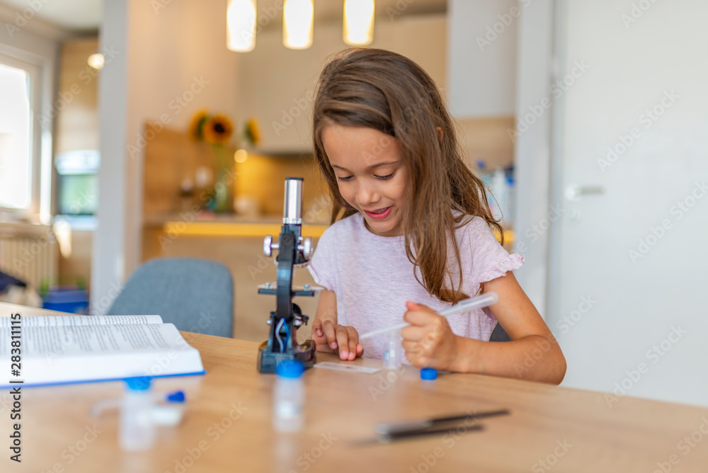 Preschool age girl looks into microscope. Child playing science in the ...