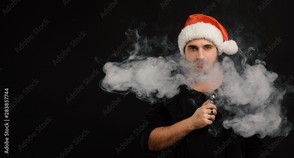 Man with beard in Santa red hat smoking electronic sigarette. vape pen ...