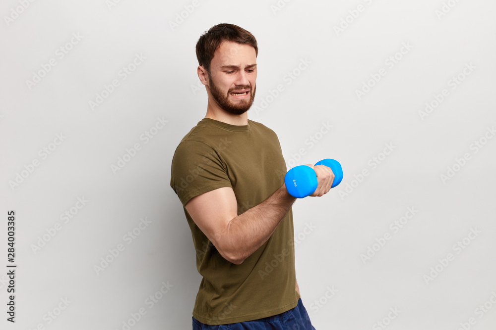 crying man raises a dumbbell with one hand with frowning face. emotion ...