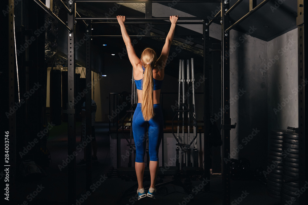 well-built girl working out at gym with modern iterior. full length ...