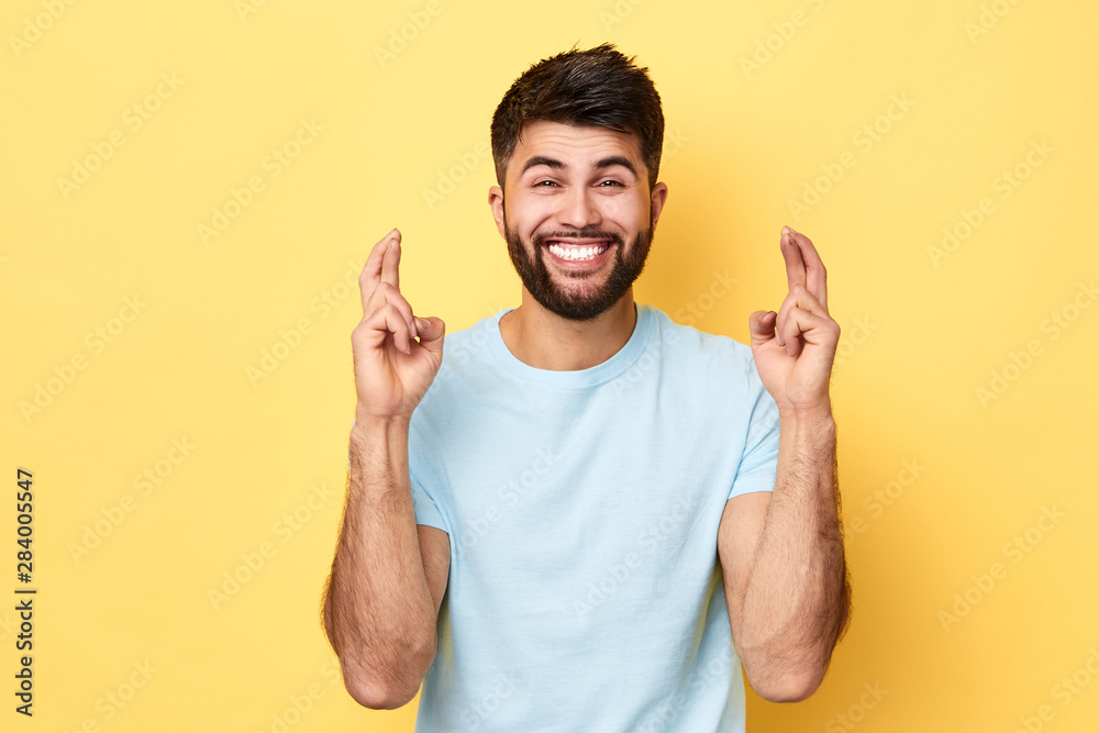 Handsome cheerful positive bearded man standing against yellow ...