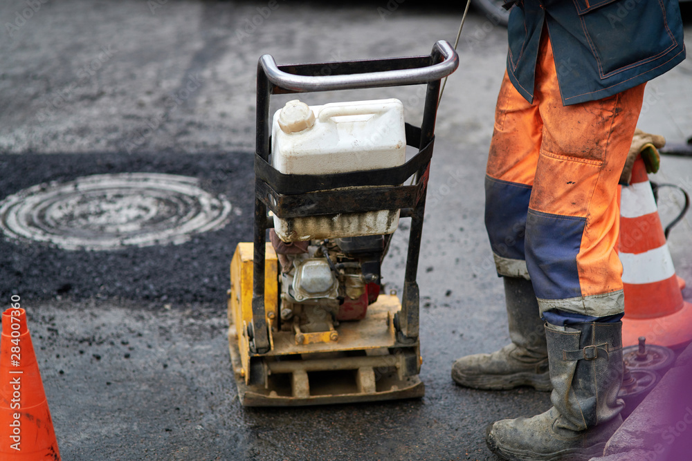 Construction worker in uniform operate vibratory plate compactor ...