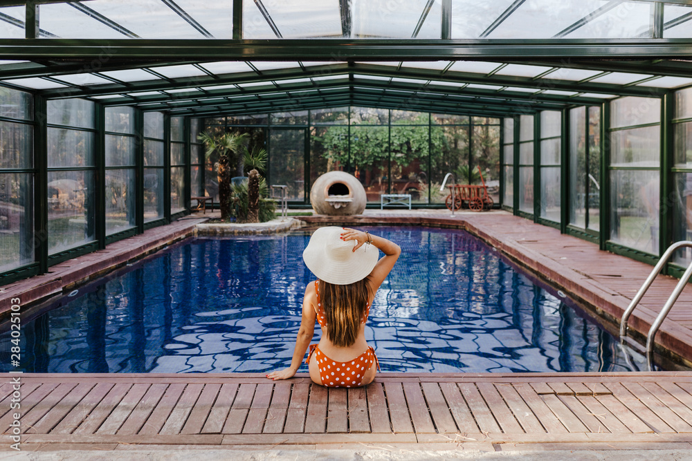 beautiful young woman relaxing in an indoor swimming pool. Summer time ...
