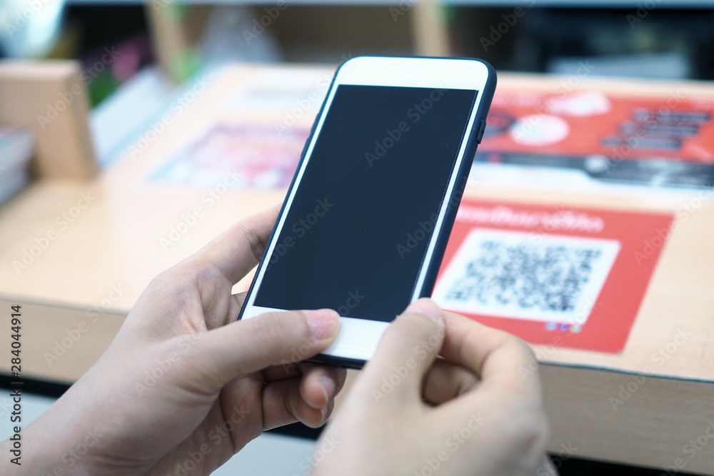Hands use the phone to scan the QR code to receive discounts on ...