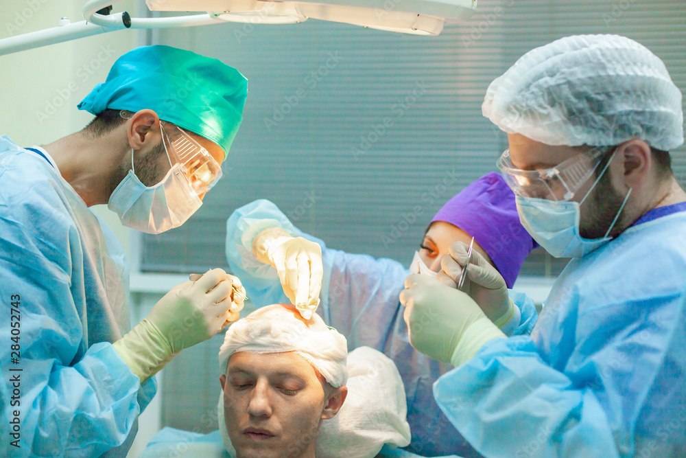 Baldness treatment. Hair transplant. Surgeons in the operating room ...