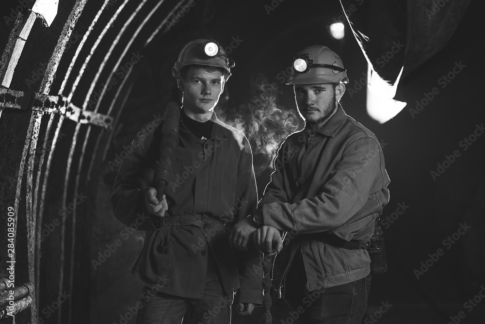 Two young guys in special clothes and helmets standing in the mine ...