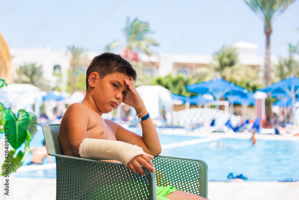 Sad kid with arm cast neer swimming pool, Child with broken arm can't ...