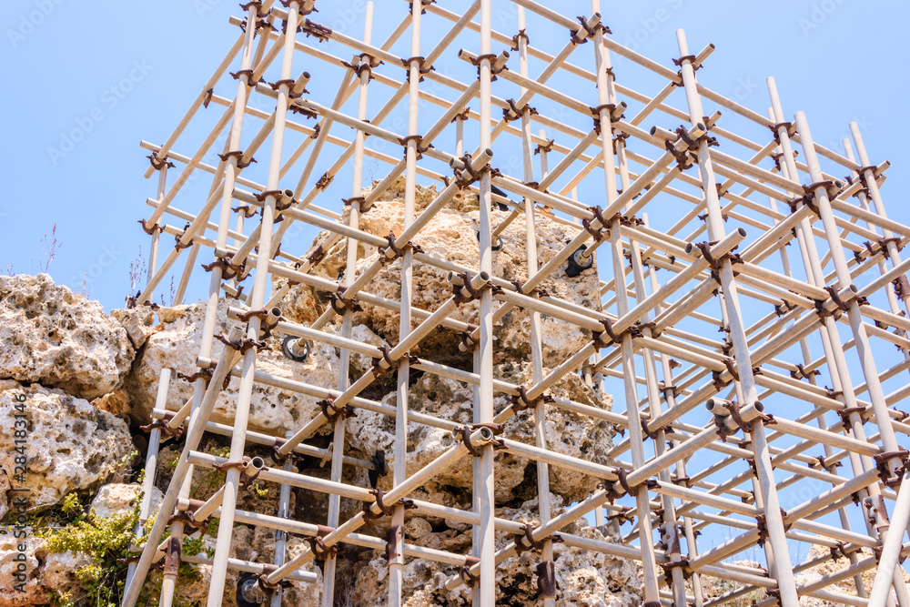 Scaffold poles hold up a weal wall of the ancient megalithic temple of ...