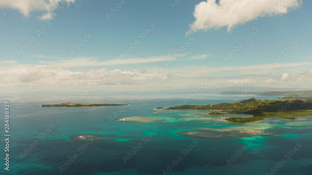 Tropical island covered with forest surrounded by an atoll and a coral ...
