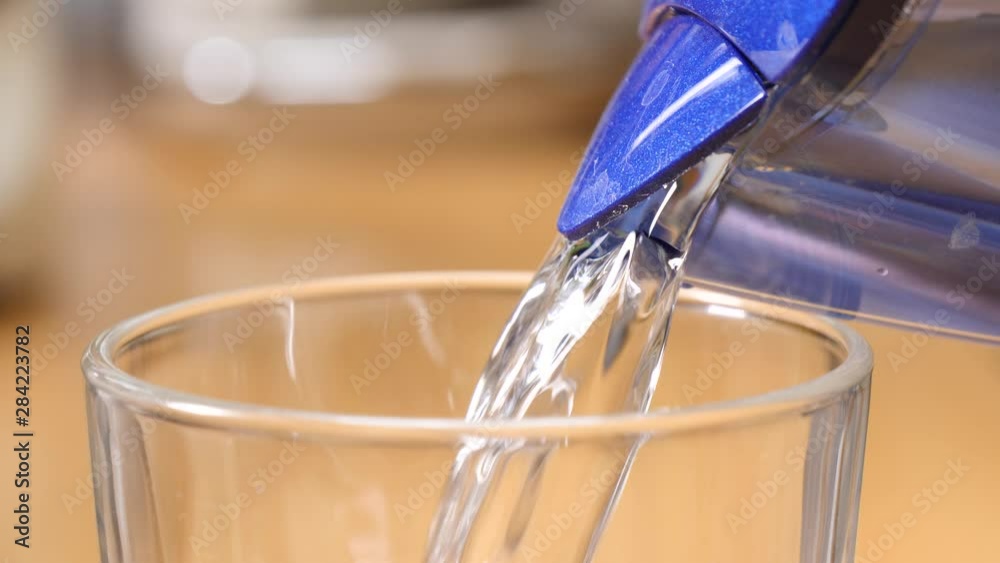 Pouring clean water from filter container into glass. Water filtration ...