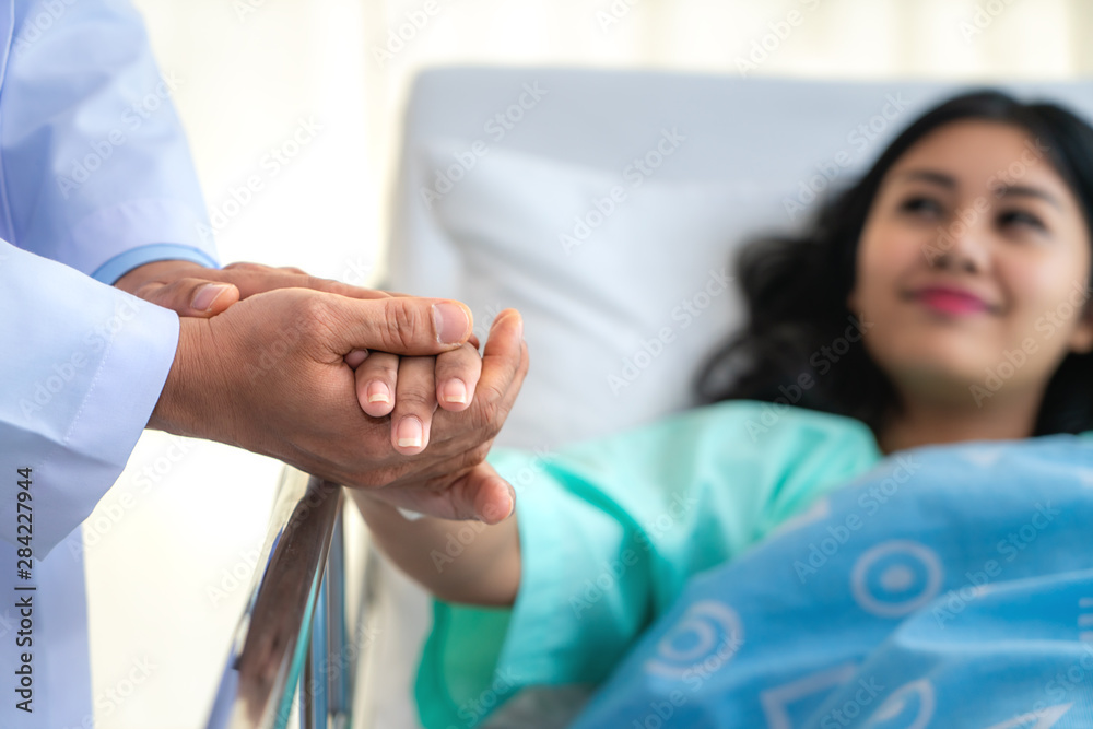 Friendly man doctor hands holding patient hand sitting at the desk for ...