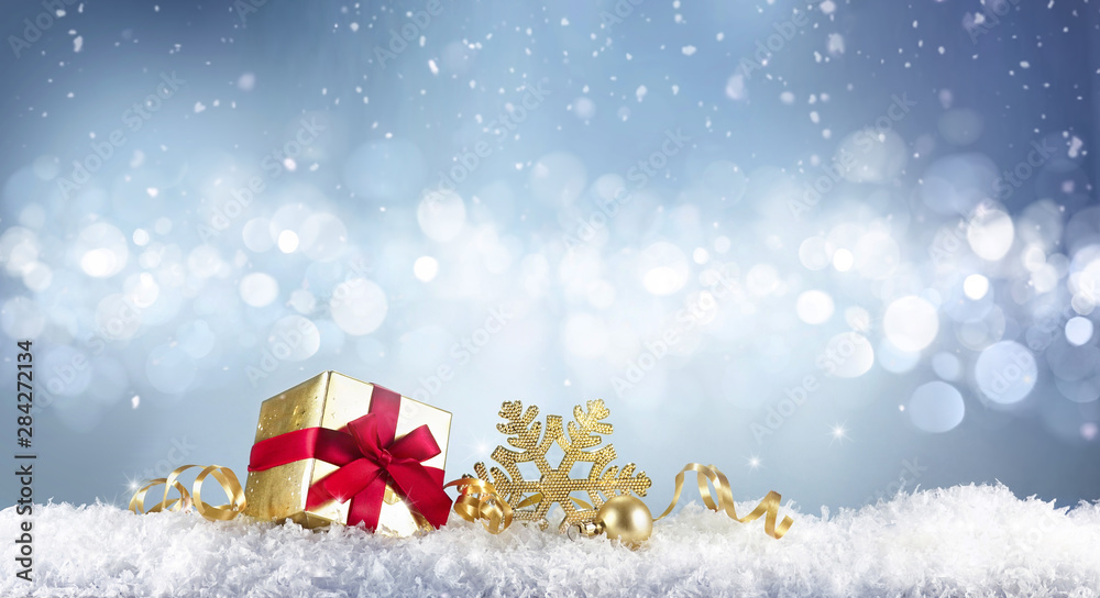 Festive Christmas snow background with copy space. Golden gift box with ...