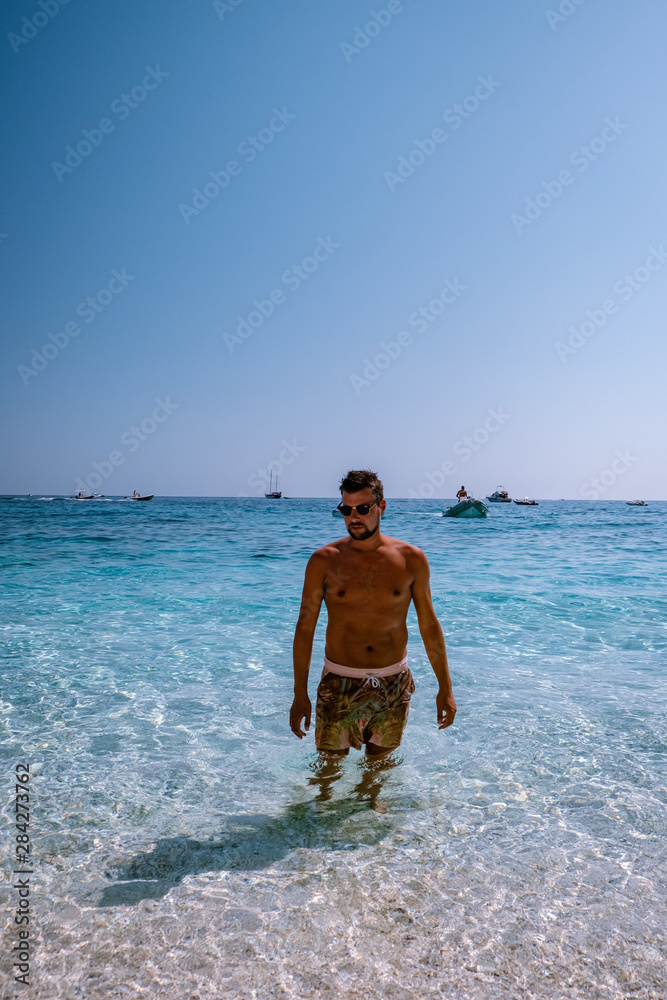 young men on the beach of Sardinia Cala Luna with pebble stones and ...
