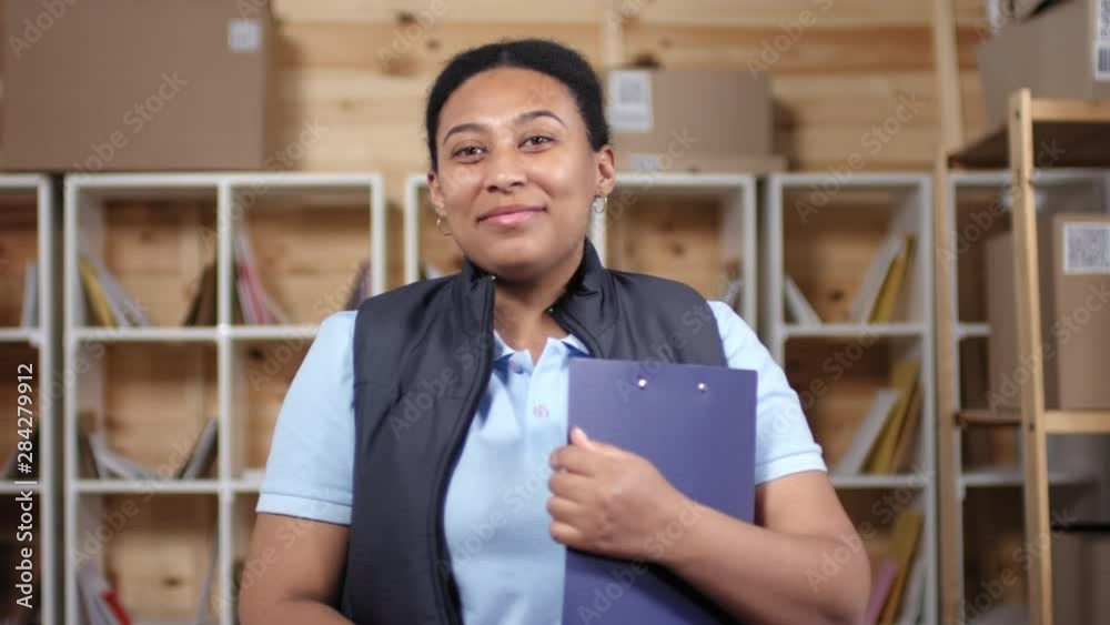 Dollying portrait shot of young black female mail service employee ...