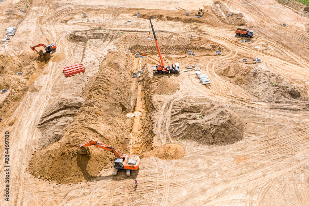 aerial top view of industrial machinery laying pipes for underground ...