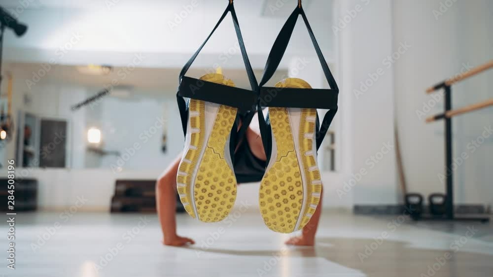 Using TRX bands, doing push-ups and torso rotations with legs suspended ...