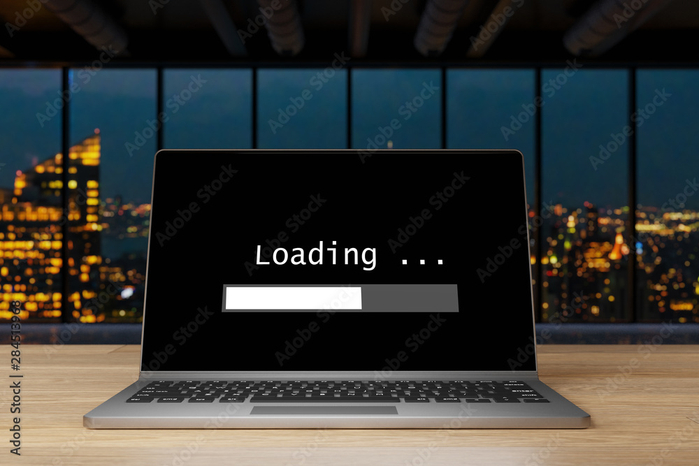 laptop on wooden desk in modern large indsutrial opffice at nighttime ...