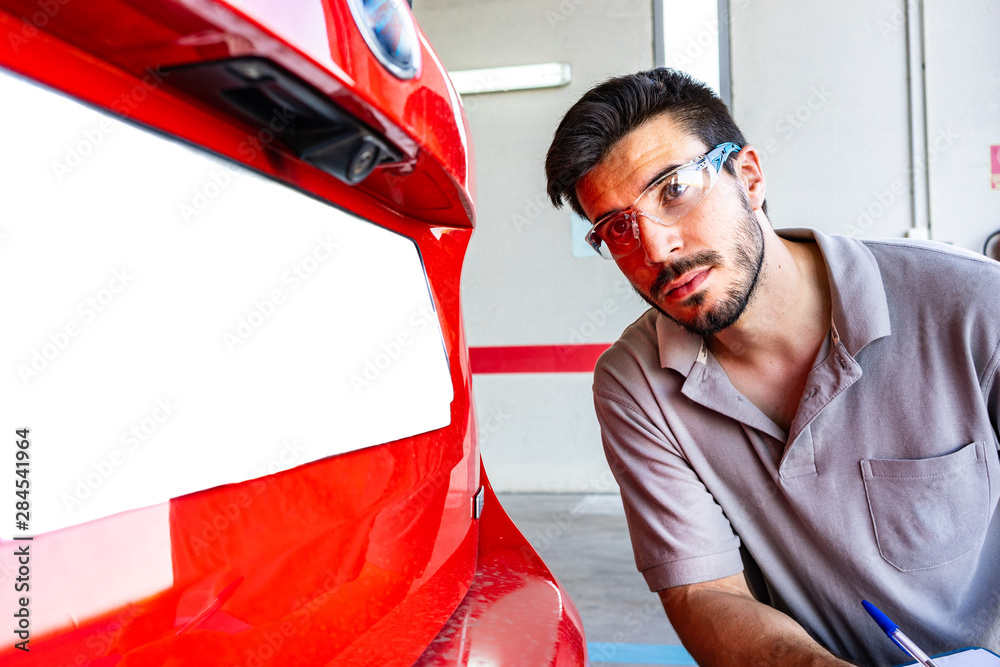 Technician with safety glasses inspecting the rear view camera of a car ...