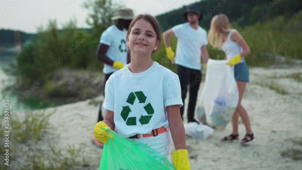 Adorable kid cleaning nature landscape from trash with environmental ...